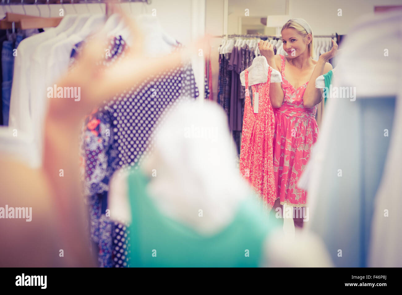 Pretty blonde holding up dress in mirror Stock Photo - Alamy