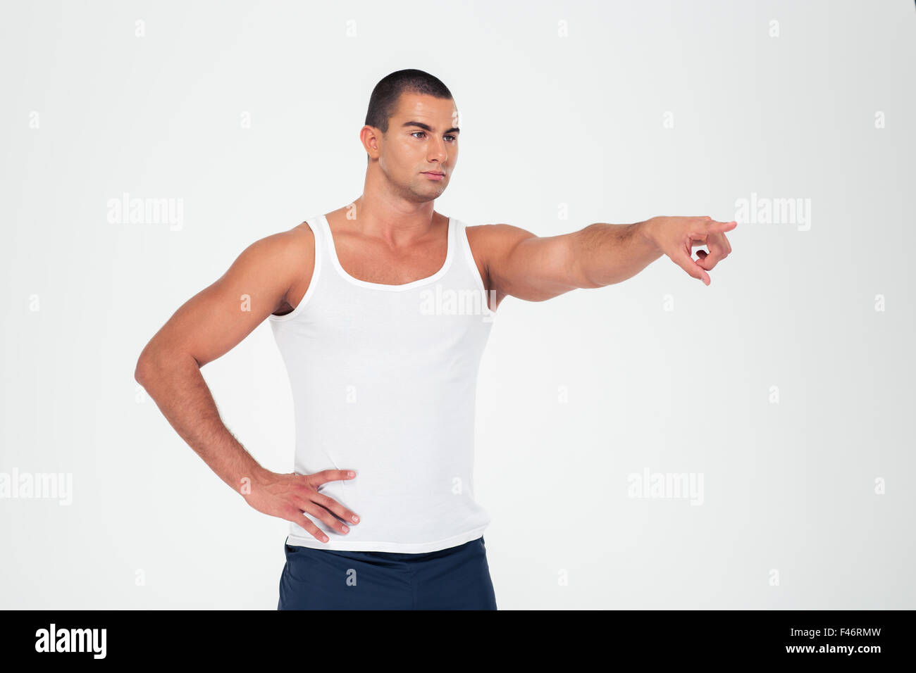 Portrait of a serious muscular man pointing finger away on something ...