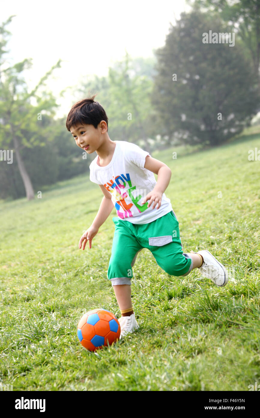 Boy playing football in field Stock Photo - Alamy
