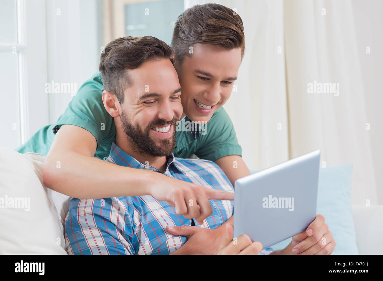 Homosexual couple men looking at tablet Stock Photo - Alamy