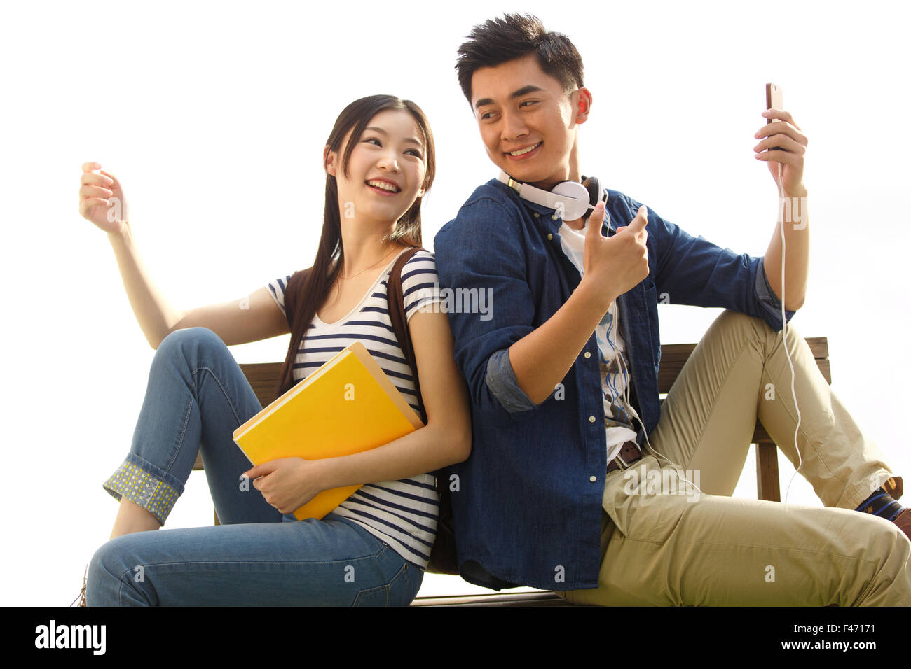 Two young people sitting back to back Stock Photo - Alamy