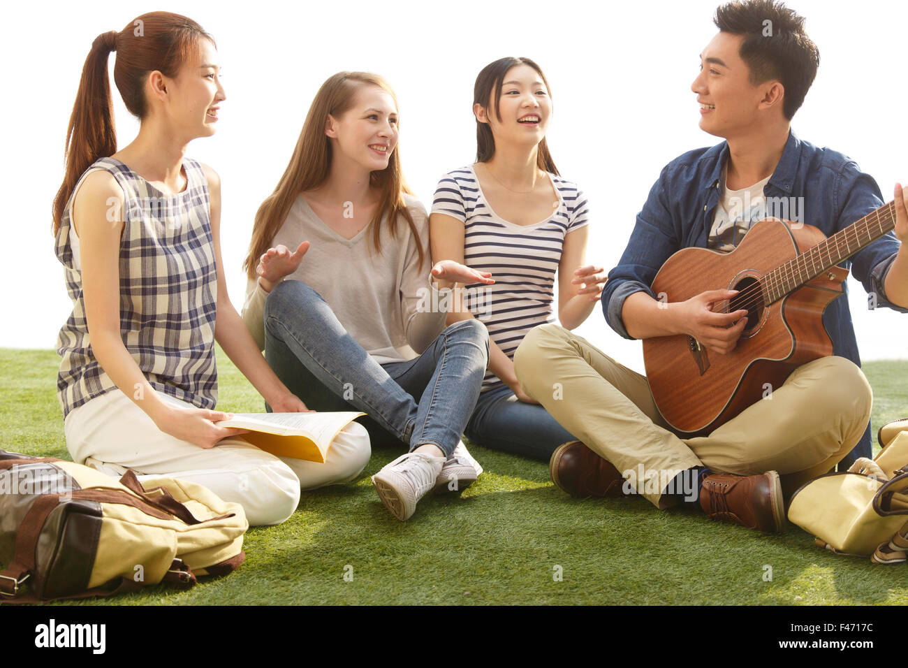 Young people sitting on lawn singing Stock Photo - Alamy