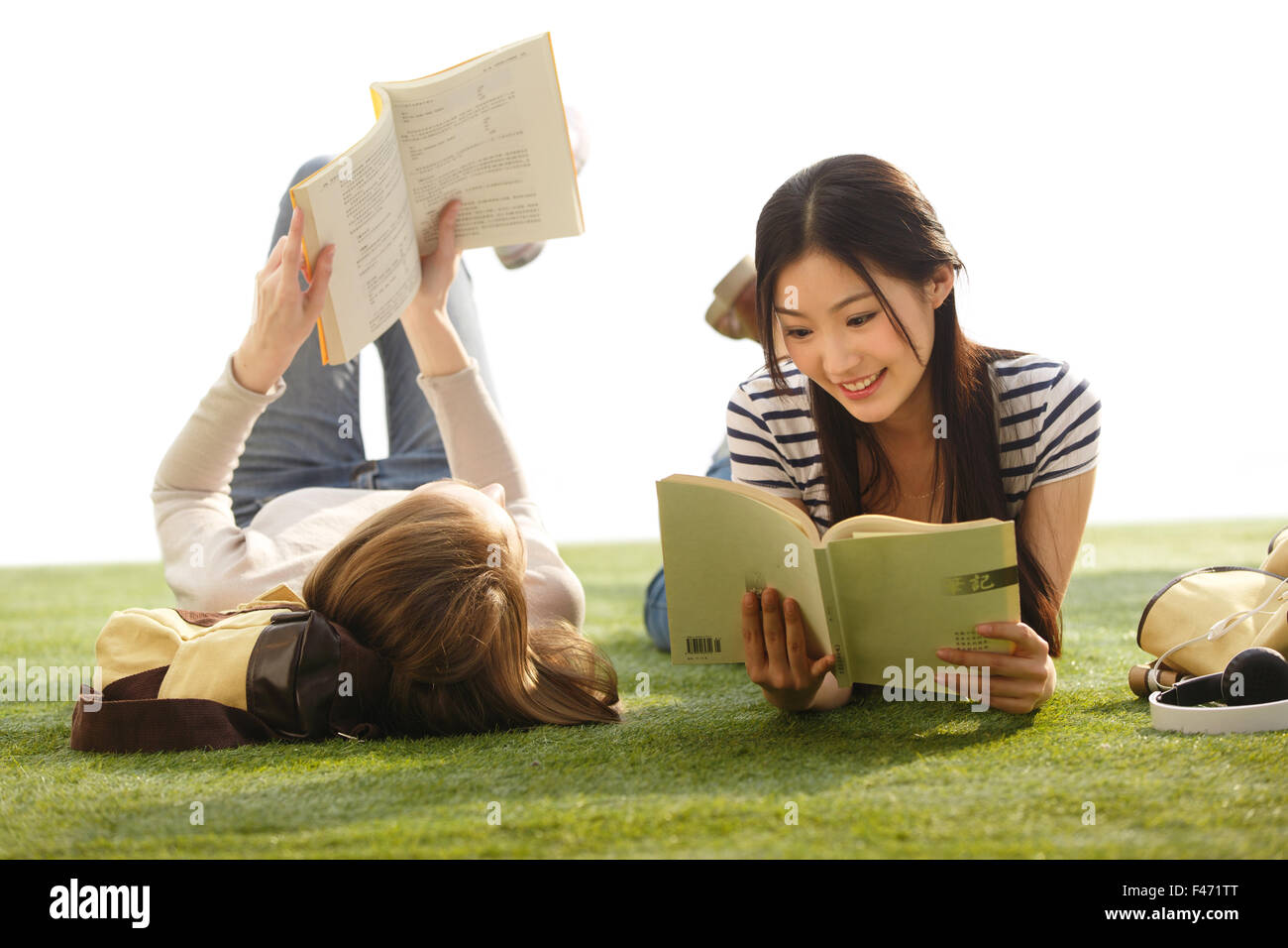Two young woman reading on lawn Stock Photo - Alamy