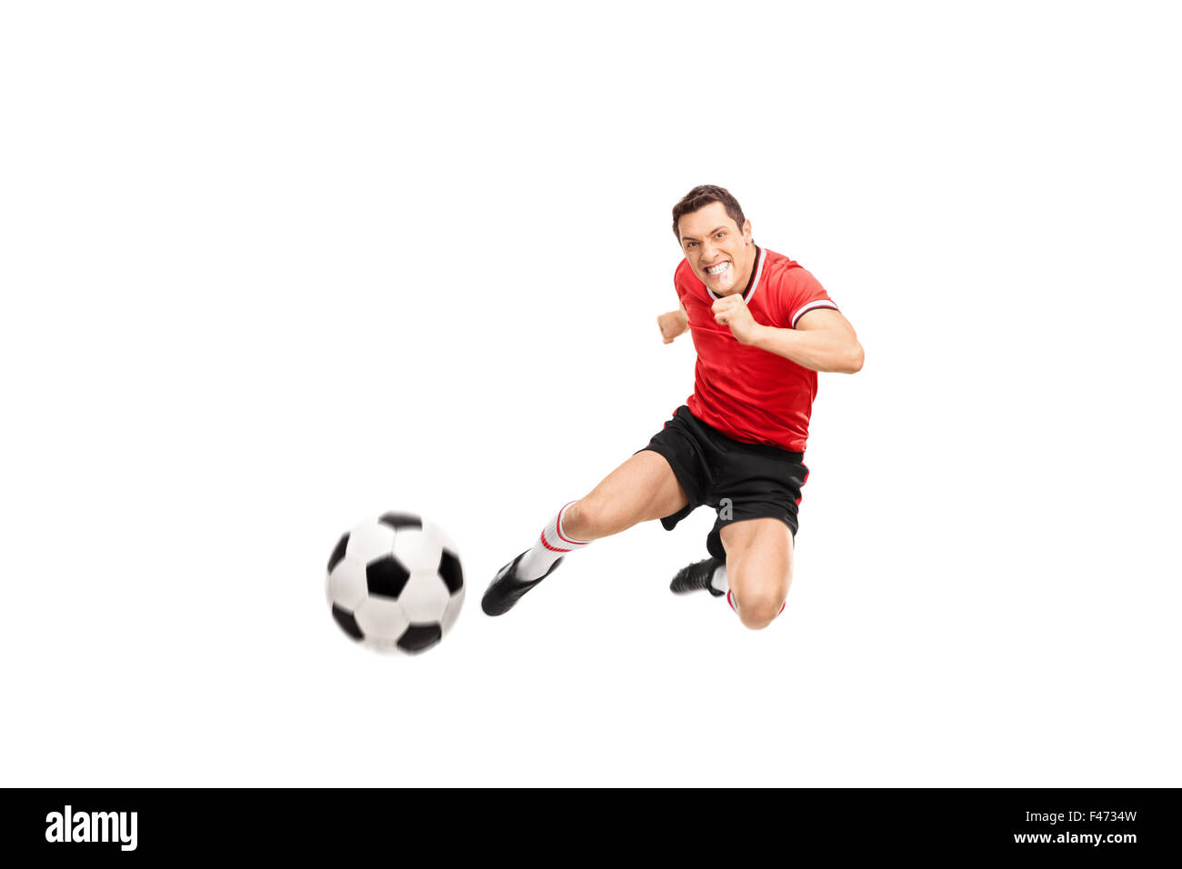 Studio shot of a young football player shooting a football towards the ...
