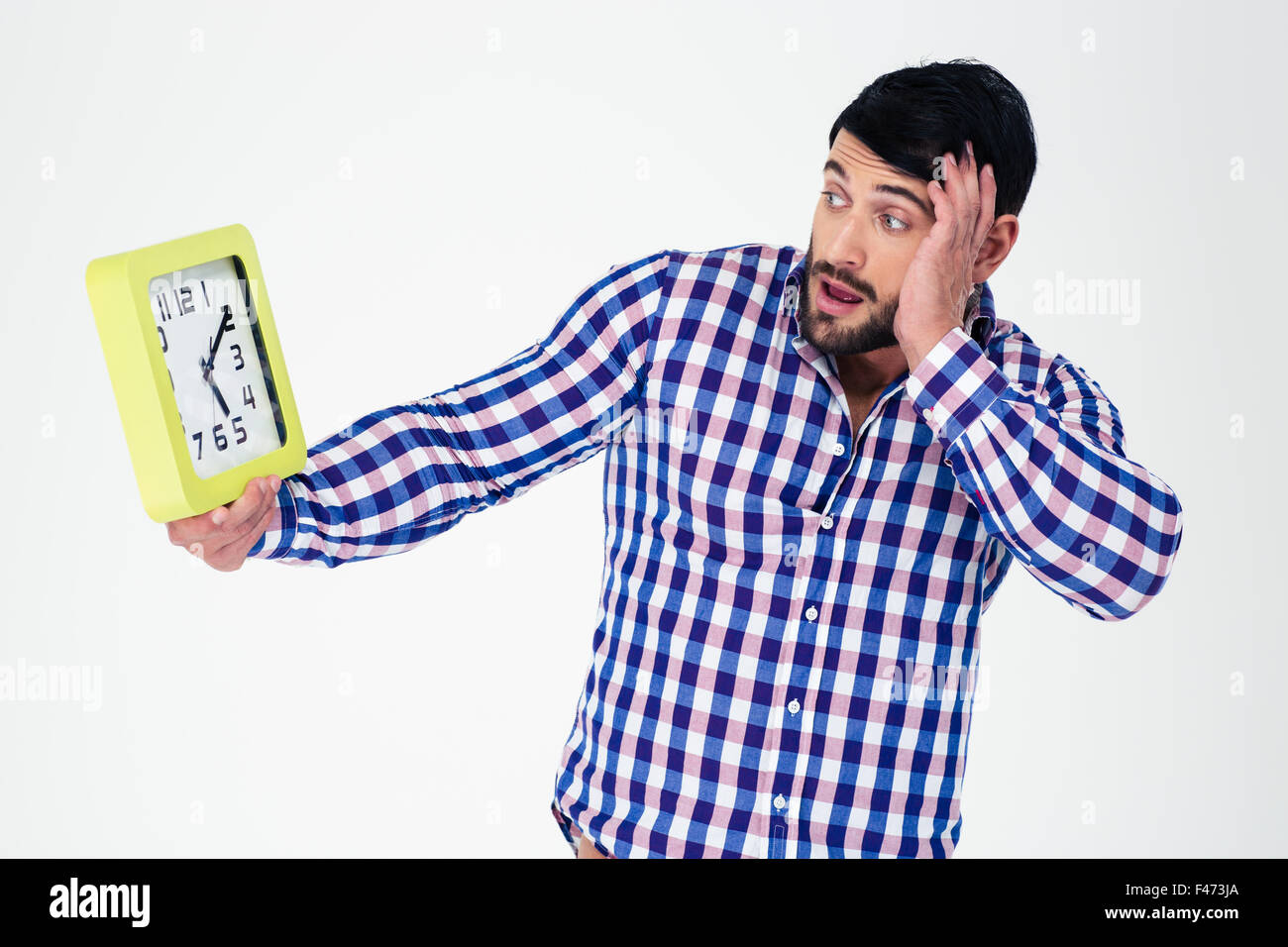 Portrait of a young man looking on wall clock isolated on a white ...