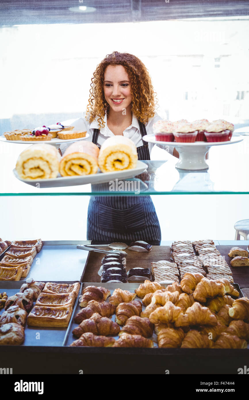 Happy pretty barista looking at cakes Stock Photo - Alamy