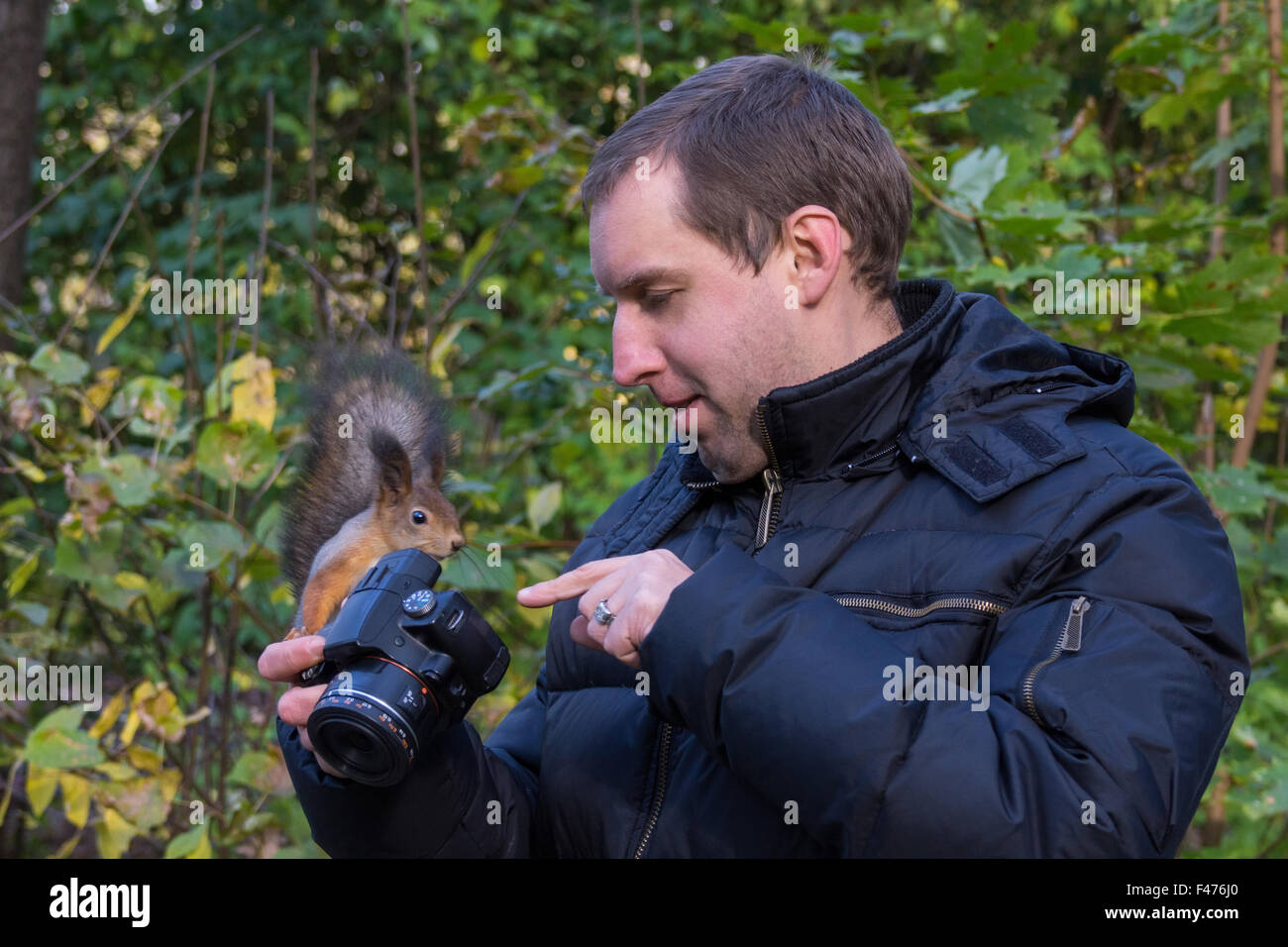 The photograph depicts a male photographer with a squirrel Stock Photo ...