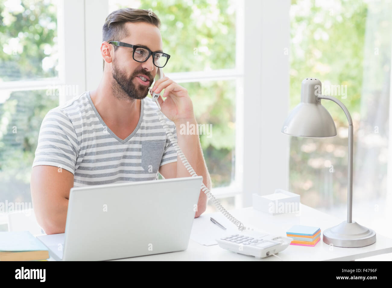 Happy handsome man having phone call and using laptop computer Stock ...