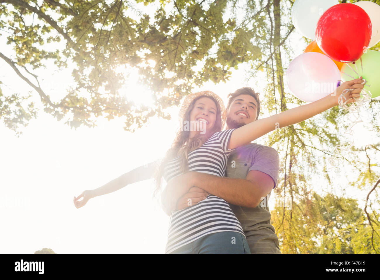 Cute couple hugging and holding balloons in the park Stock Photo - Alamy
