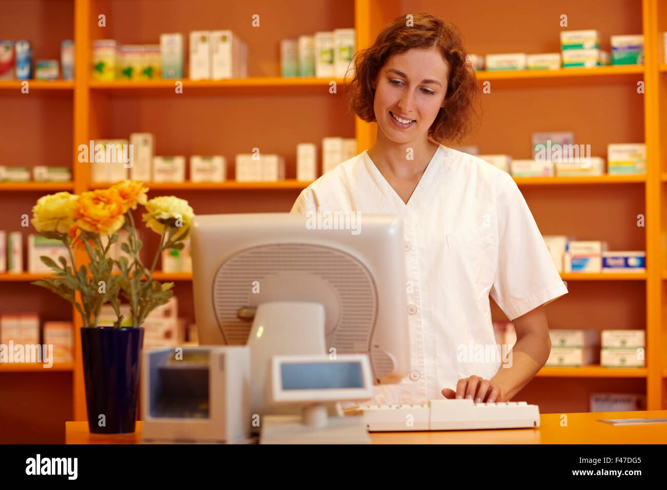 Pharmacist typing on computer behind pharmacy counter Stock Photo - Alamy