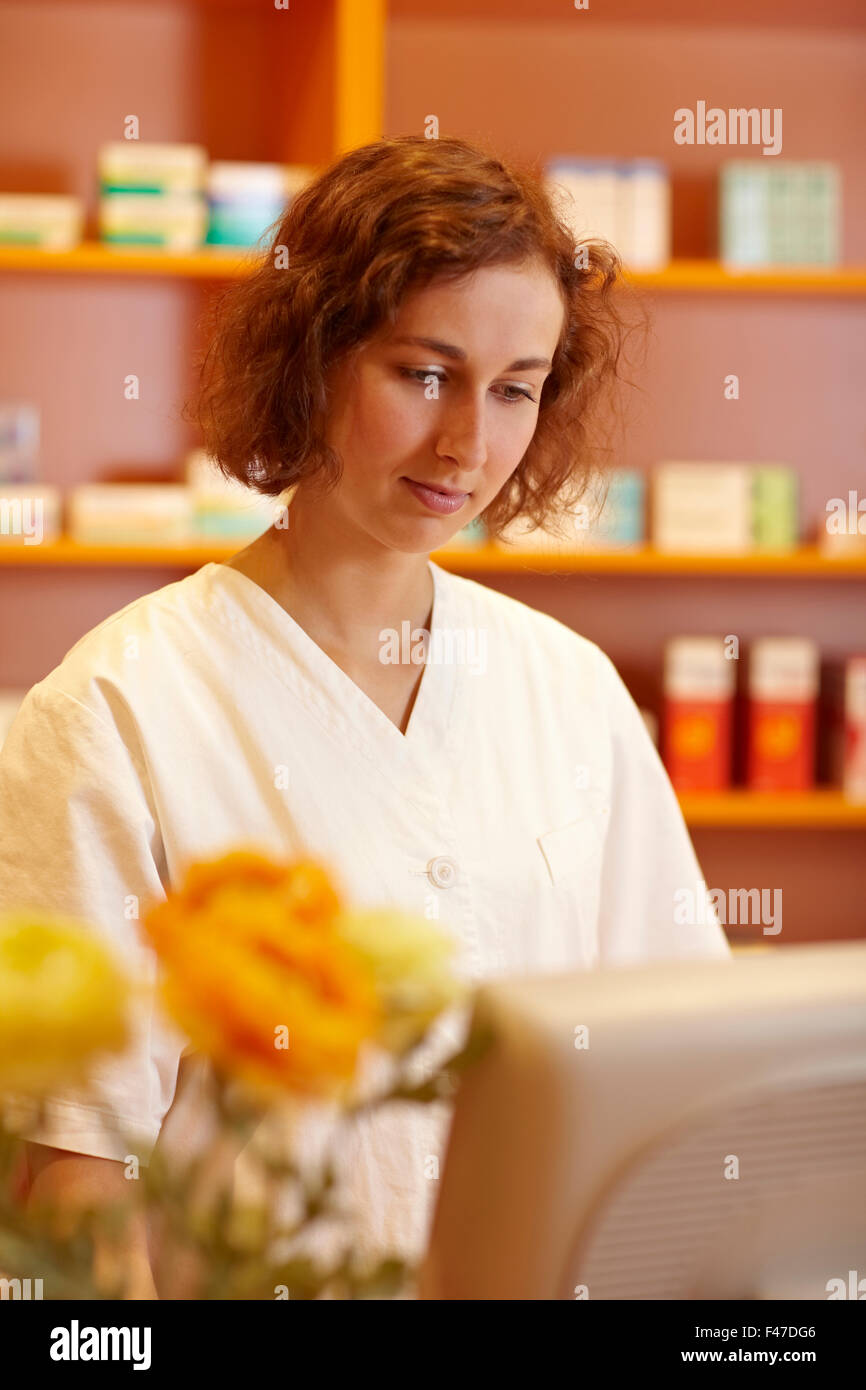 Pharmacist typing on computer behind pharmacy counter Stock Photo - Alamy