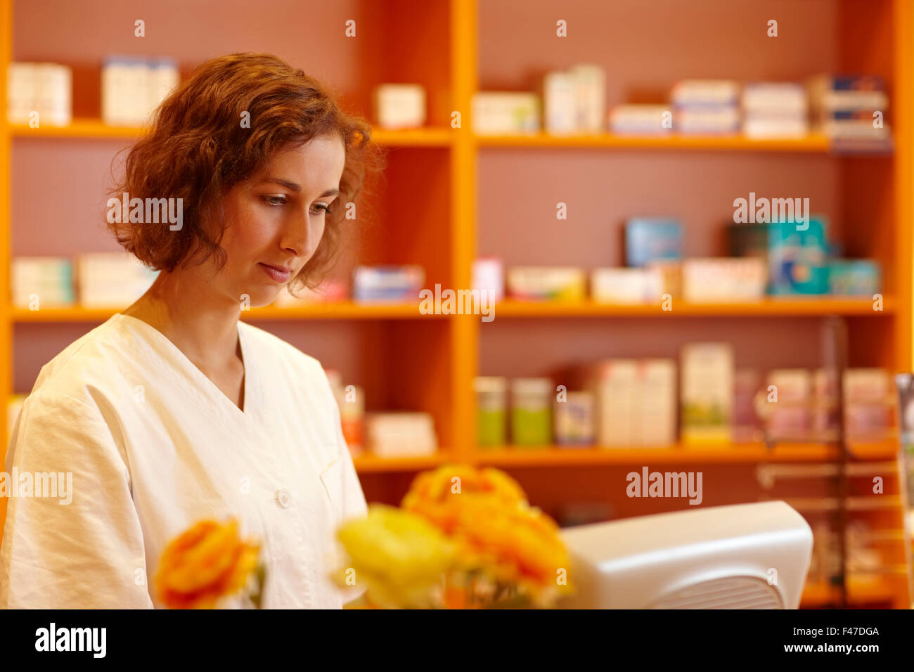 Pharmacist typing on computer behind pharmacy counter Stock Photo - Alamy