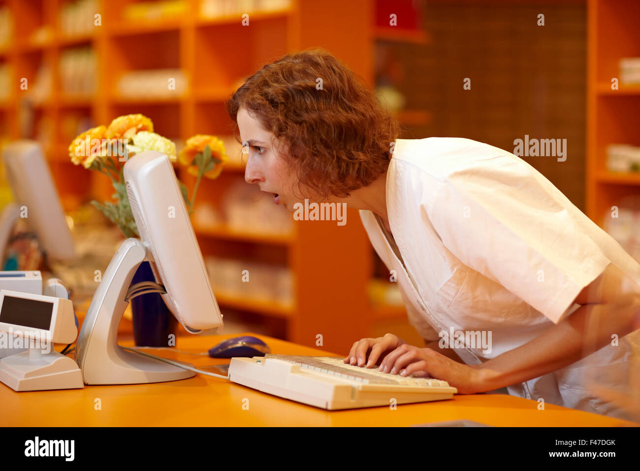 Pharmacist looking surprised at computer monitor in pharmacy Stock ...