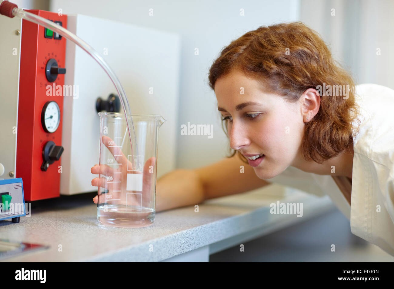 Pharmacist looking at measuring cup in laboratory Stock Photo - Alamy