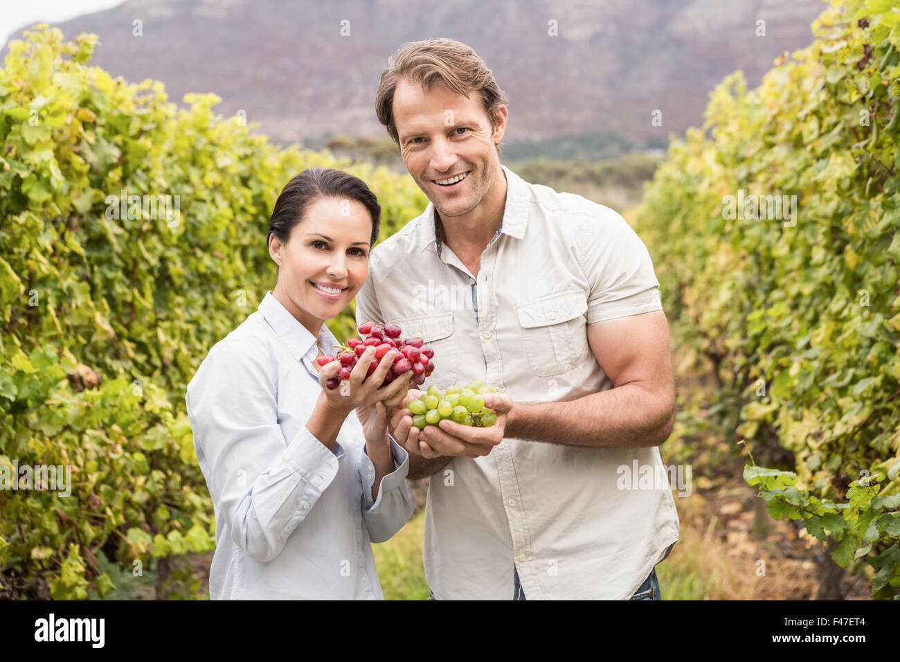 Smiling couple showing a bunch of grapes Stock Photo - Alamy
