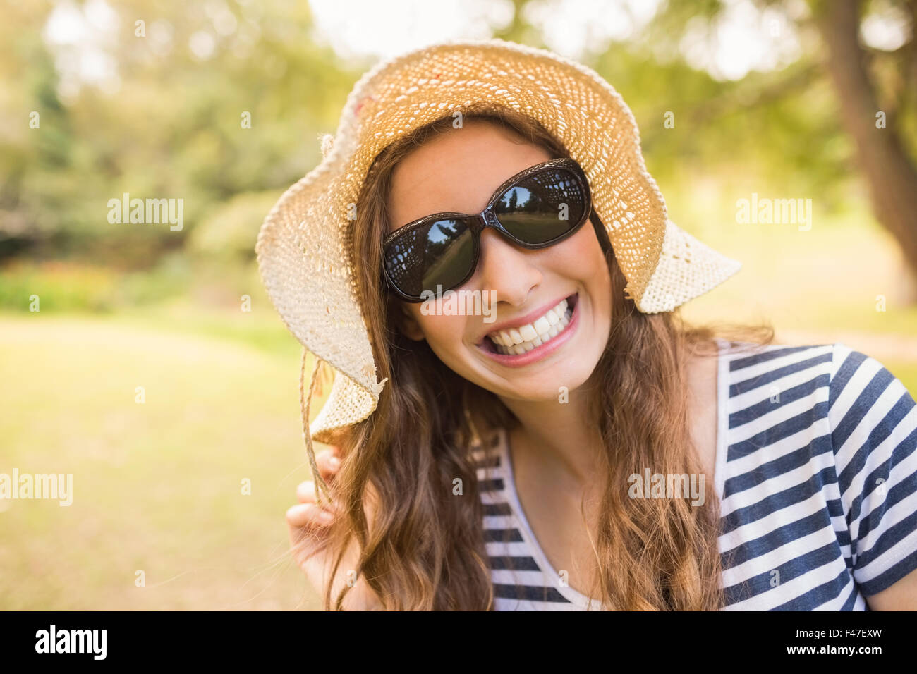 Pretty brunette wearing straw hat and looking at camera Stock Photo - Alamy