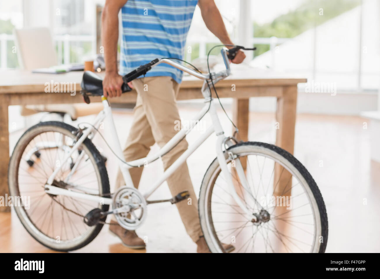 Creative businessman pushing his bike Stock Photo - Alamy