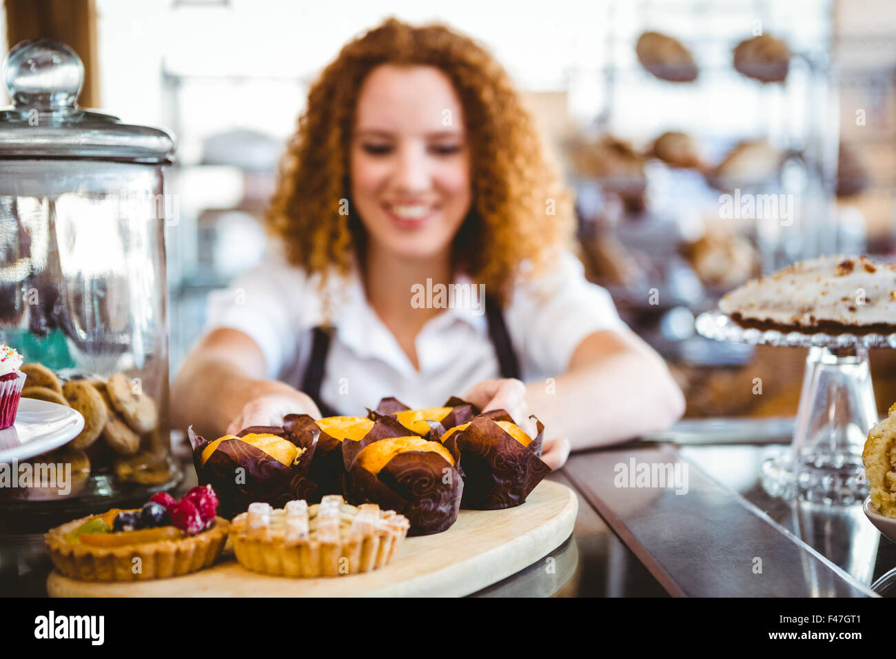 Pretty barista preparing plate with cakes Stock Photo - Alamy
