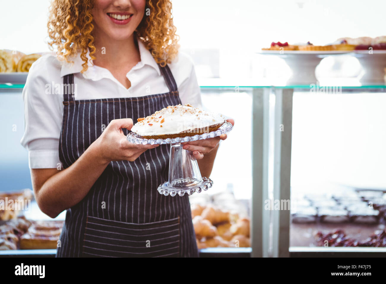 Happy pretty barista holding plate with cake Stock Photo - Alamy