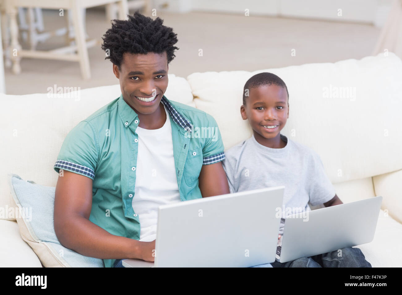 Father and son using laptops on the couch Stock Photo - Alamy