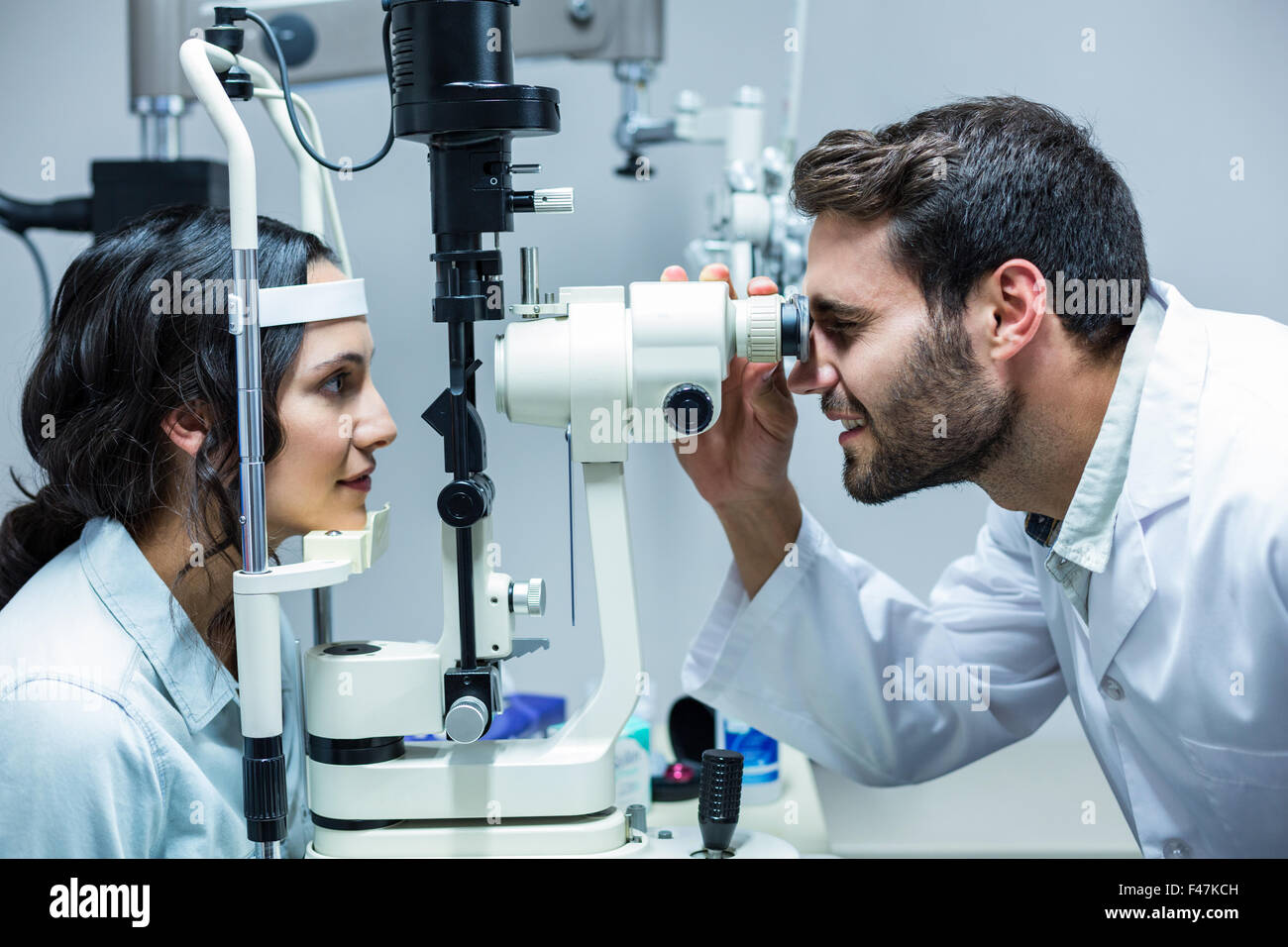 Optician examining womans eyes through slit lamp Stock Photo - Alamy