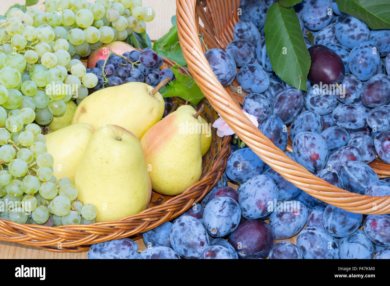Fresh fruit baskets. Fresh plums, grapes and pears in wooden baskets ...