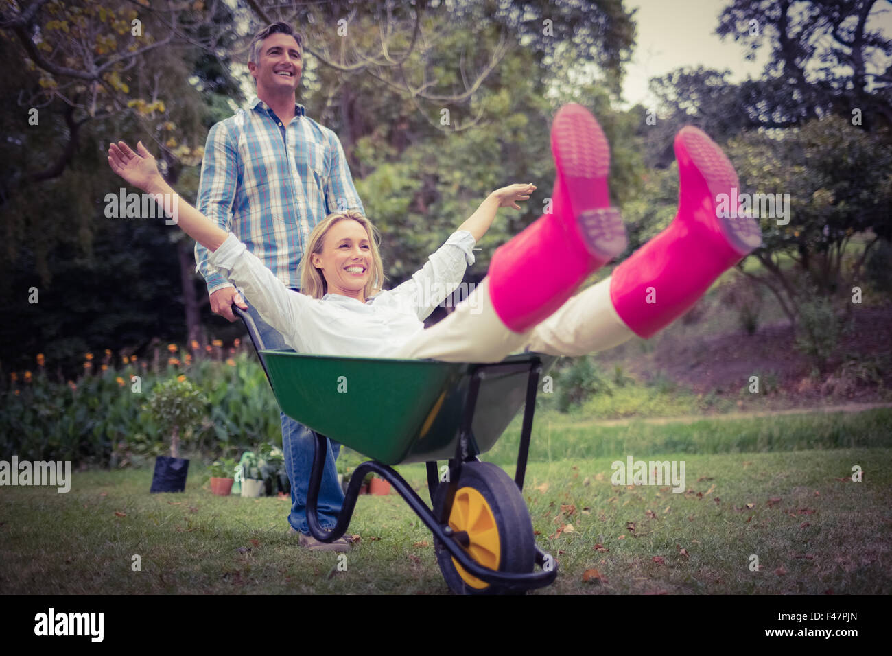 Happy couple playing with a wheelbarrow Stock Photo - Alamy