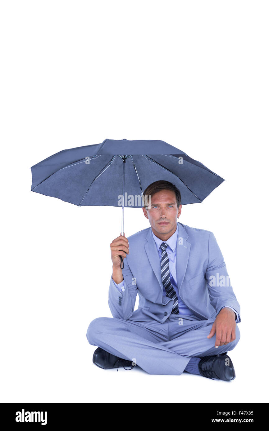 Businessman sheltering under umbrella Stock Photo - Alamy