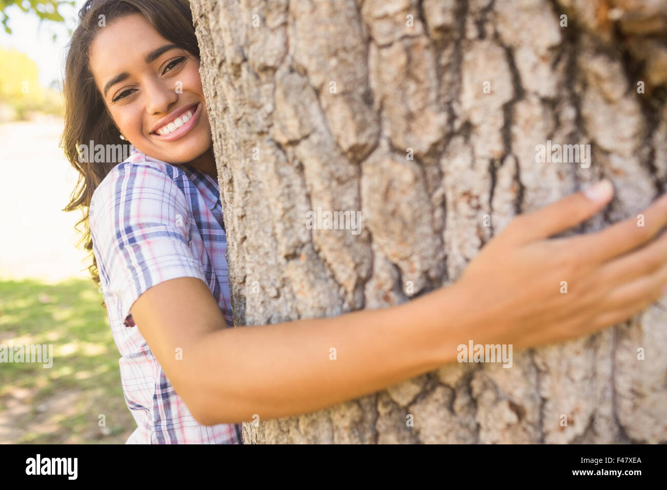 Pretty brunette hugging tree Stock Photo - Alamy