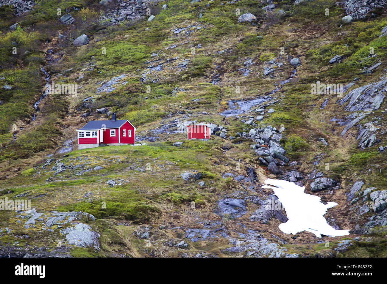Typical red Norwegian house between high mounatins in summer Stock ...