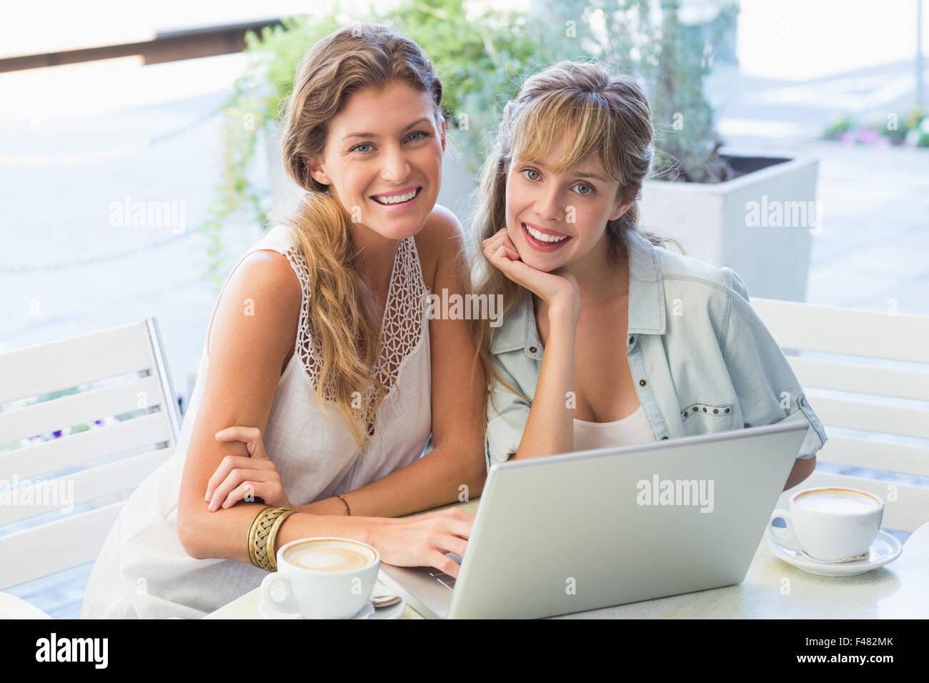 Beautiful women using laptop and smiling at the camera Stock Photo - Alamy