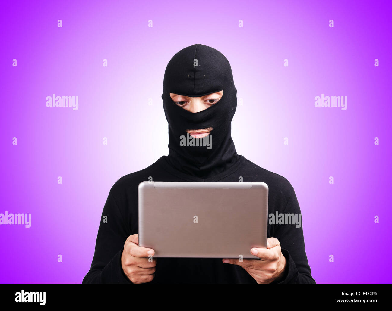 Hacker with computer wearing balaclava Stock Photo - Alamy