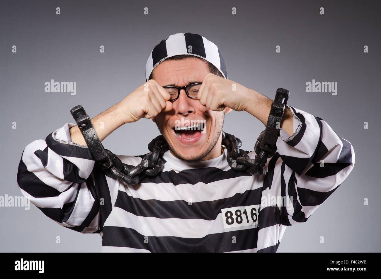 Funny prisoner in chains isolated on gray Stock Photo - Alamy