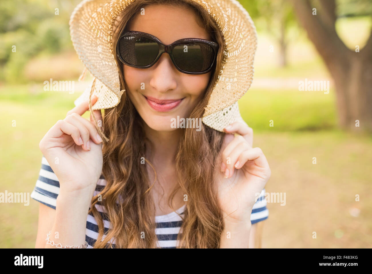 Pretty brunette wearing straw hat and looking at camera Stock Photo - Alamy