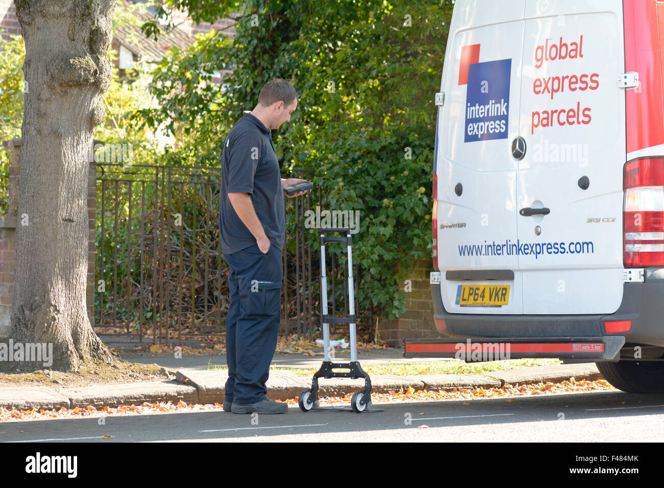 Interlink Express delivery man standing at rear of van checking ...