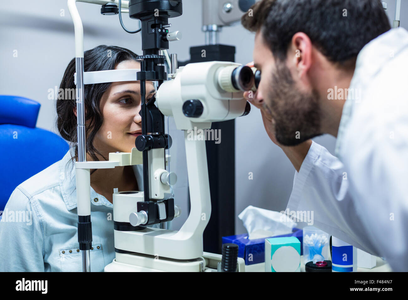 Optician examining womans eyes through slit lamp Stock Photo - Alamy