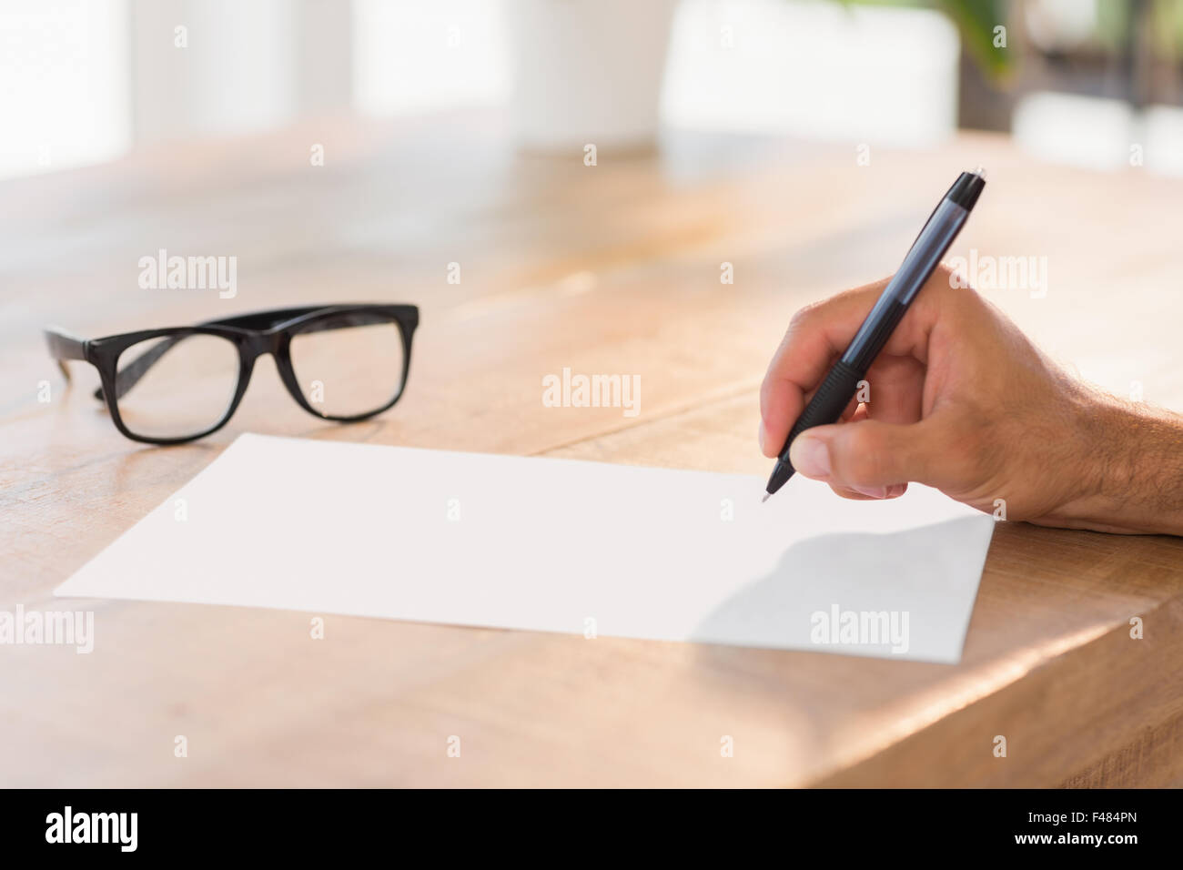 Side view of hand writing on white page on working desk Stock Photo - Alamy