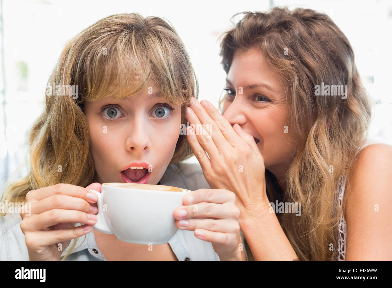 Beautiful women sitting and whispering secrets Stock Photo - Alamy