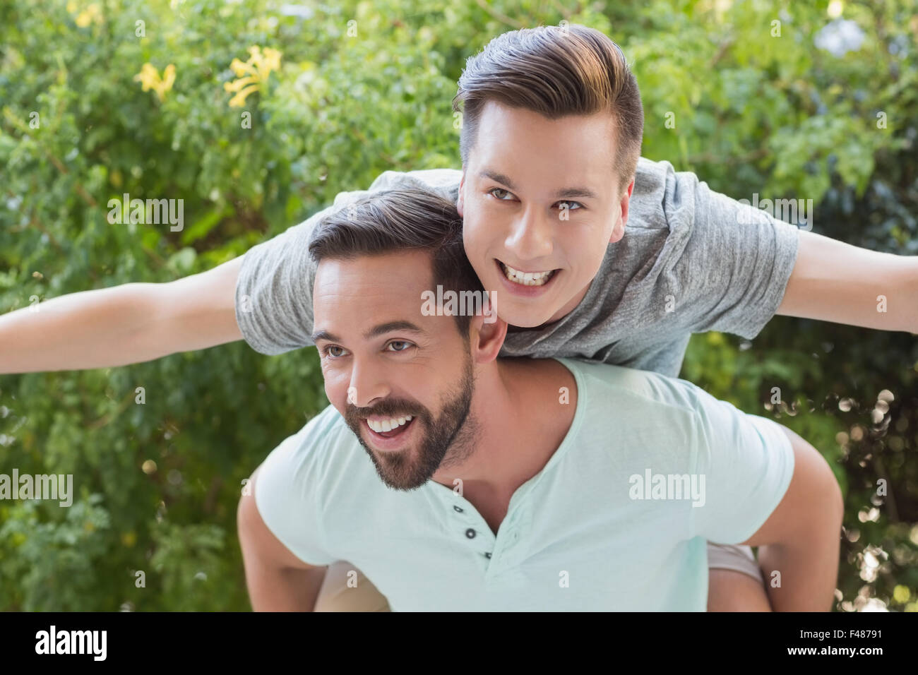 Man giving piggy back to his boyfriend Stock Photo - Alamy
