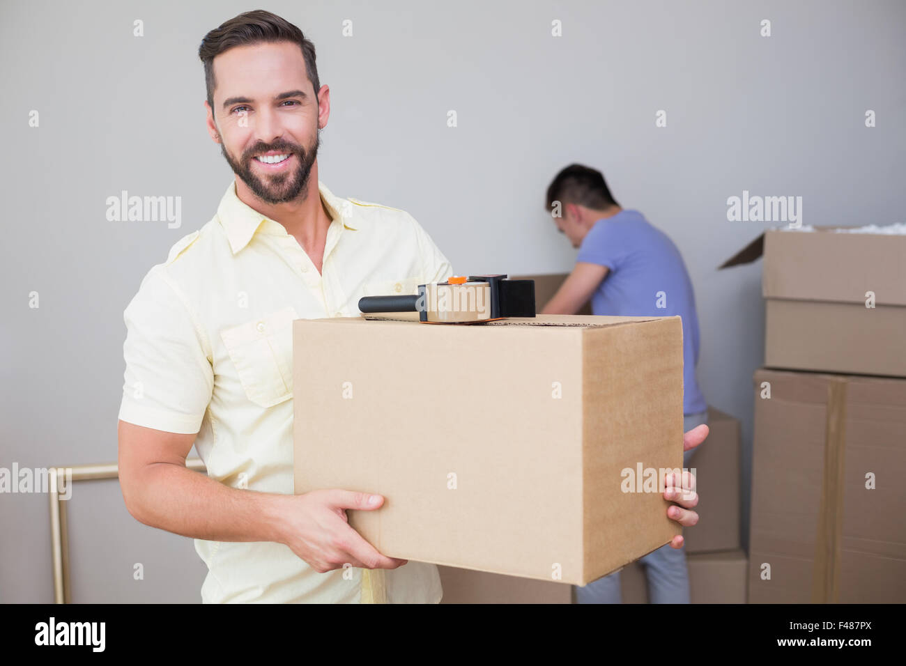 Handsome man holding box with his boyfriend behind Stock Photo - Alamy