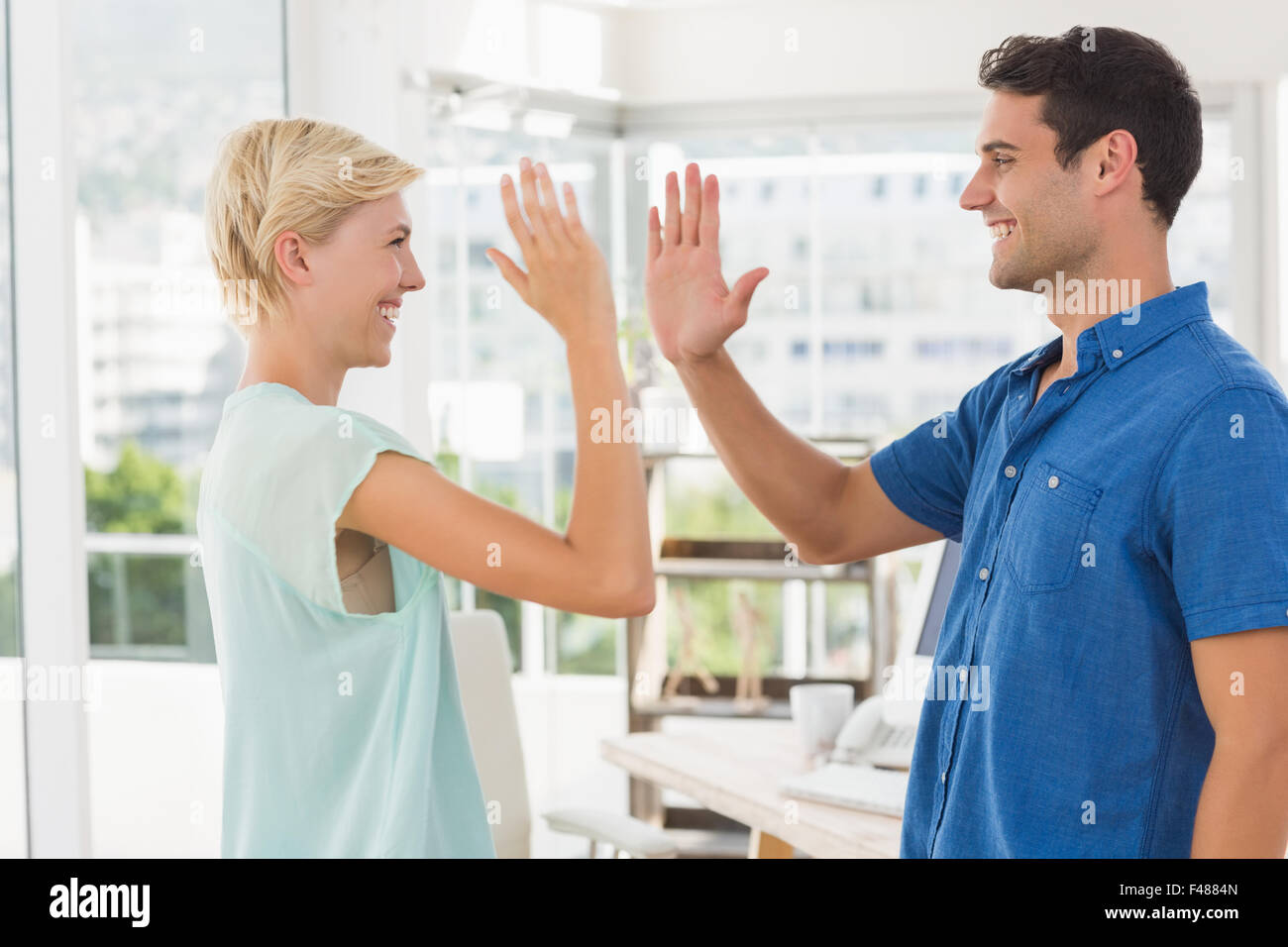 Happy creative business people high fiving Stock Photo - Alamy