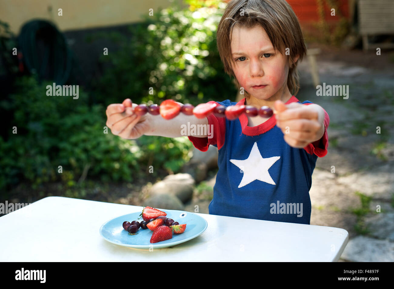 Boy eating berries on a skewer, Sweden Stock Photo - Alamy