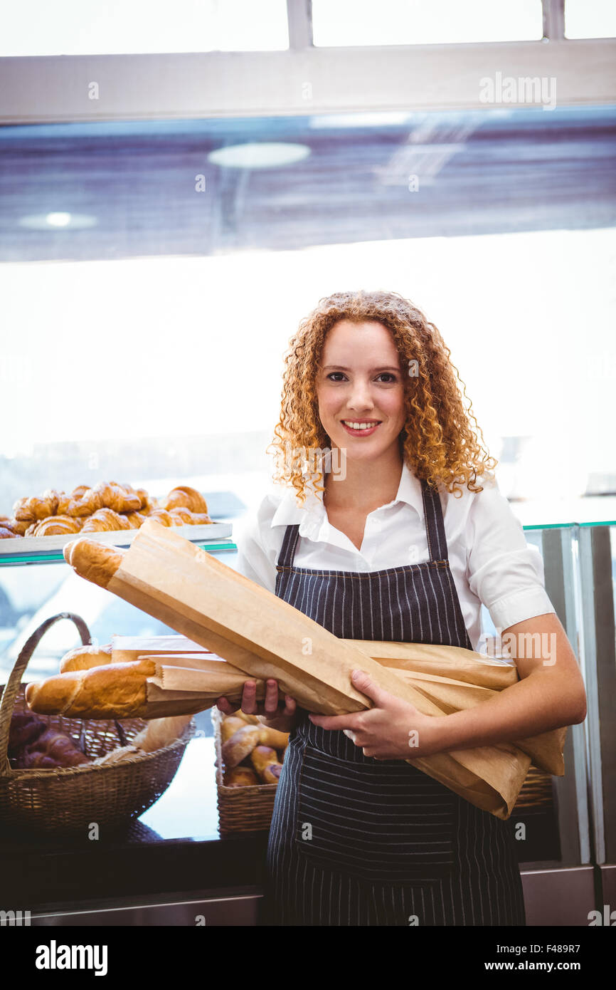 Happy pretty barista holding bread Stock Photo - Alamy