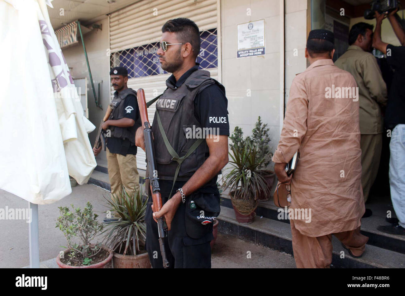 Security staffs cordon off bank after a robbery attempt, in Landhi area ...