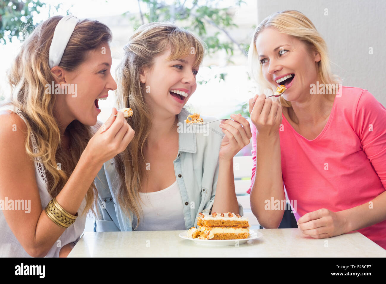 Beautiful women smiling and eating cake Stock Photo - Alamy