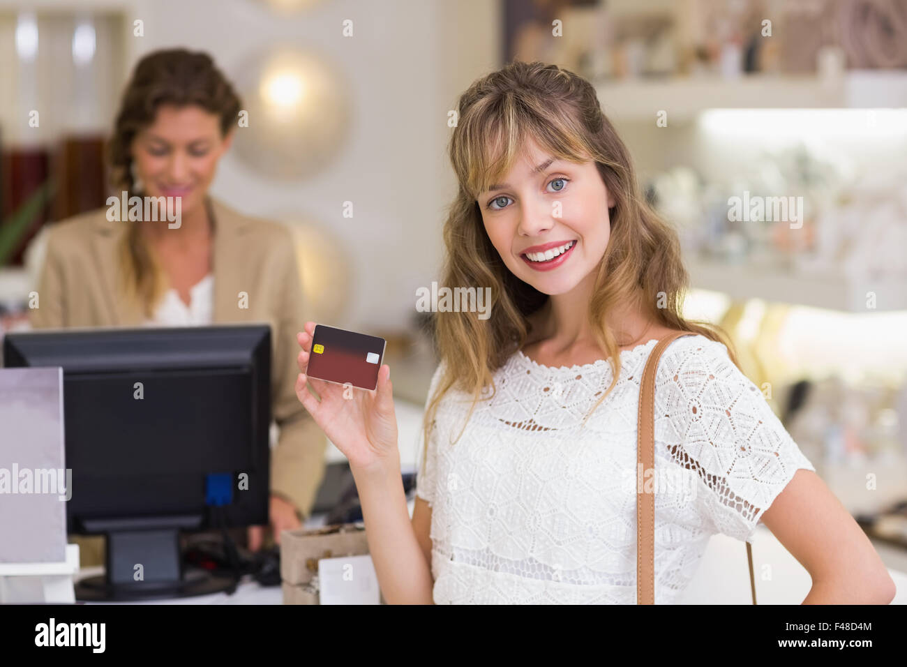 Beautiful customer at cash register holding credit card Stock Photo - Alamy