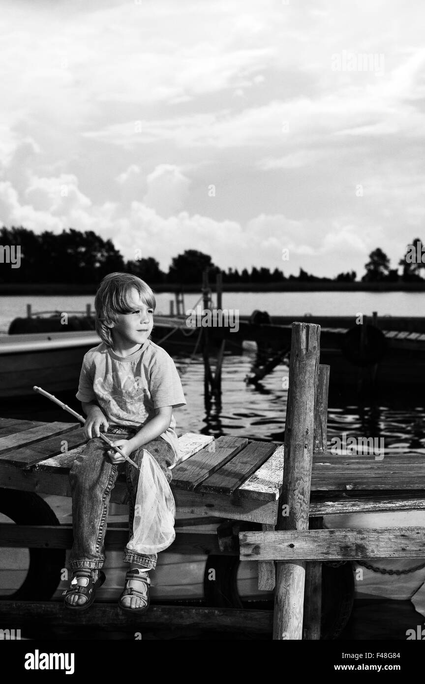 Boy sitting on a jetty, Sweden Stock Photo - Alamy