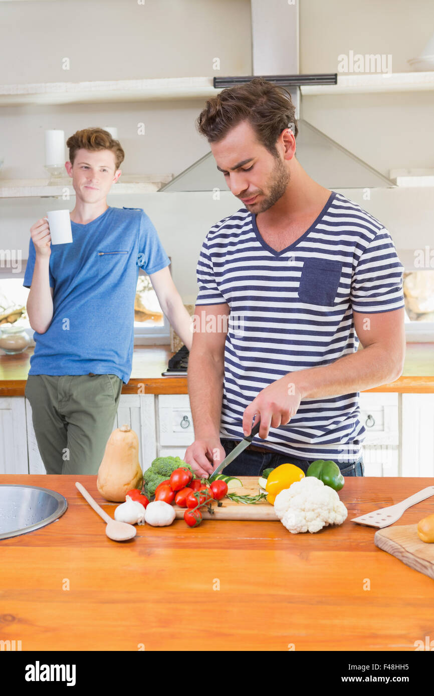 Handsome man cutting vegetables with boyfriend behind Stock Photo - Alamy