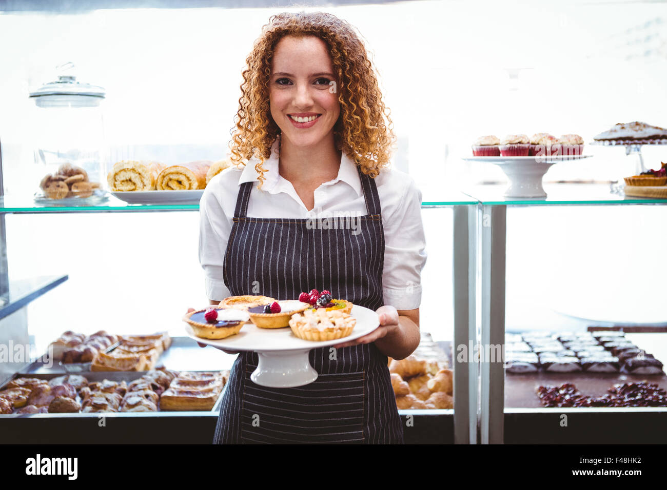 Happy pretty barista holding plate with cake Stock Photo - Alamy