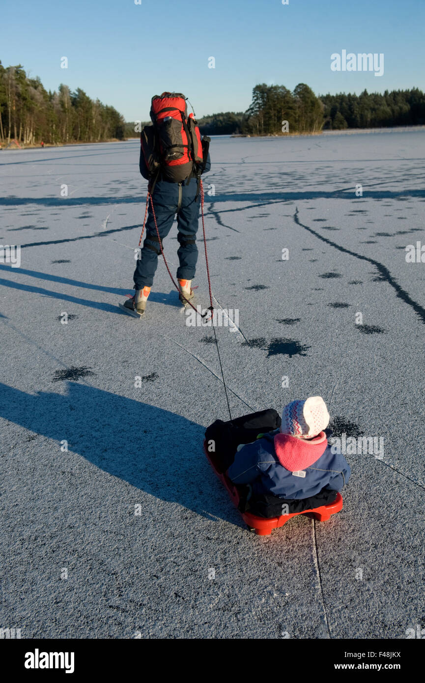 Man skating with a child in a little sledge, Sweden Stock Photo - Alamy